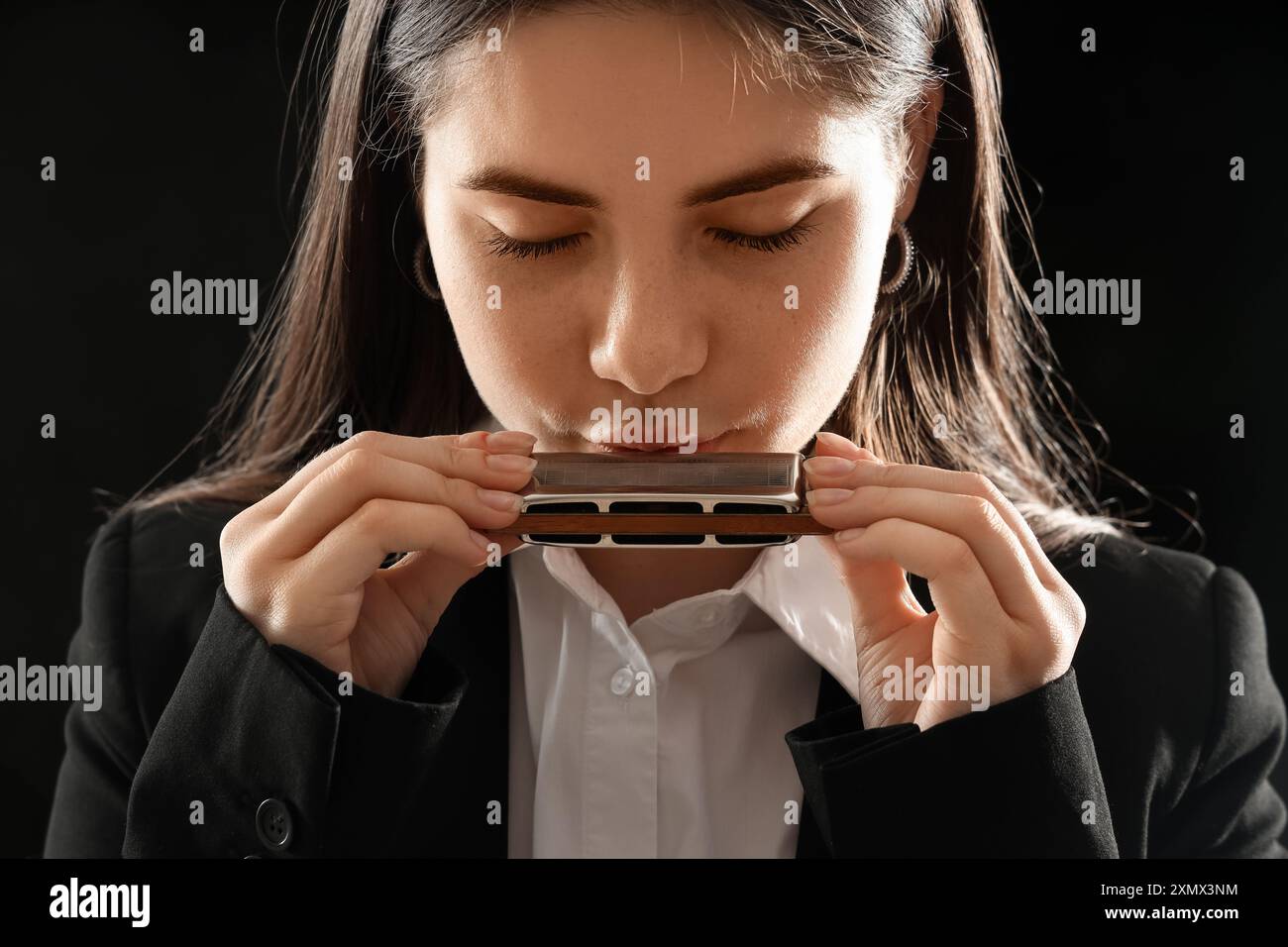 Female artist playing harmonica on dark background, closeup Stock Photo ...