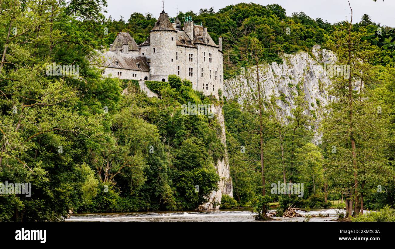 Walzin Castle on a rocky hill protruding from lush green trees next to ...
