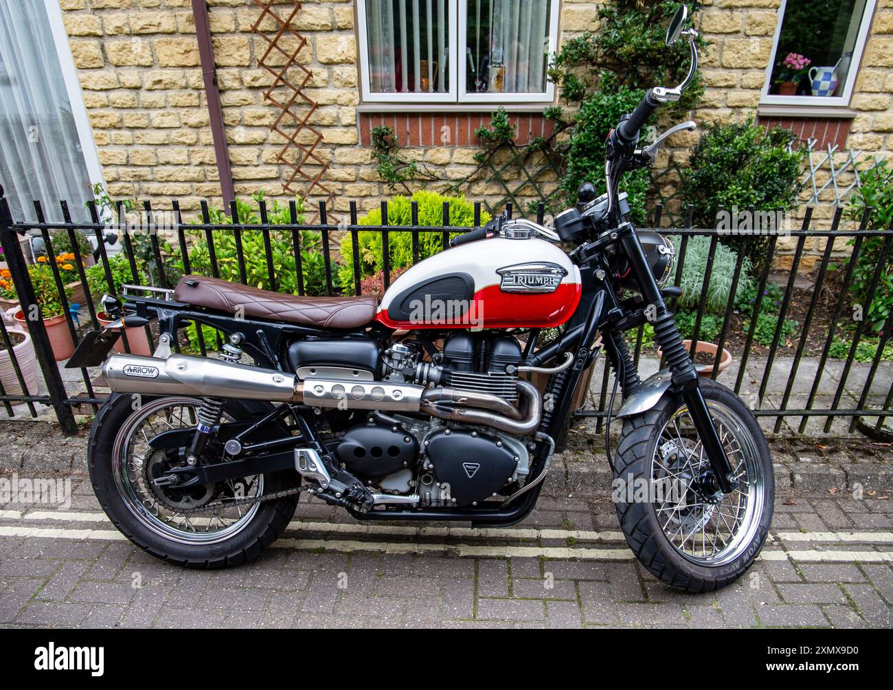 A Triumph Bonneville motorcycle is parked in front of a residential ...