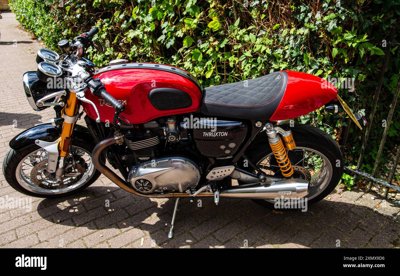 Red and black Triumph Thruxton motorcycle parked on a brick pavement ...