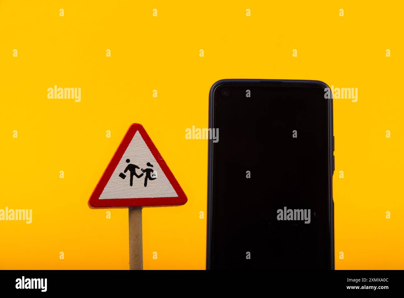 A playful wooden "DANGER KIDS" sign is paired with a smartphone against ...