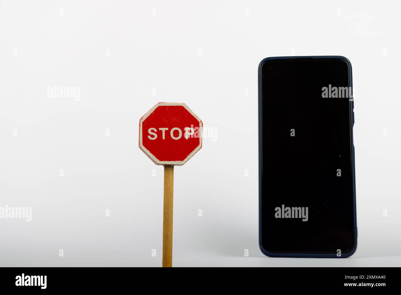On a white background, a wooden toy stop sign stands next to a ...
