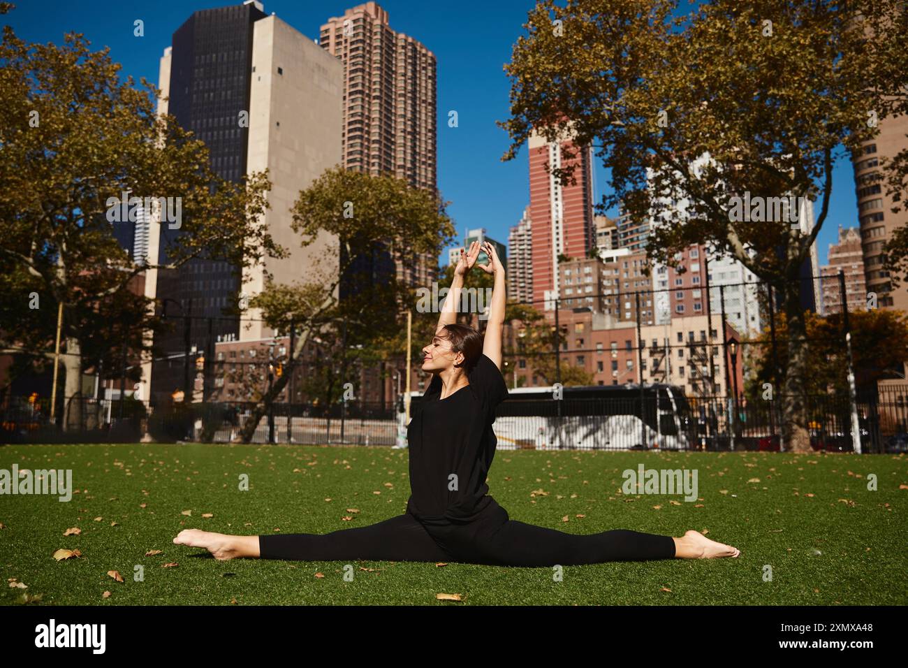Woman splits on NYC lawn with tall buildings in view Stock Photo - Alamy