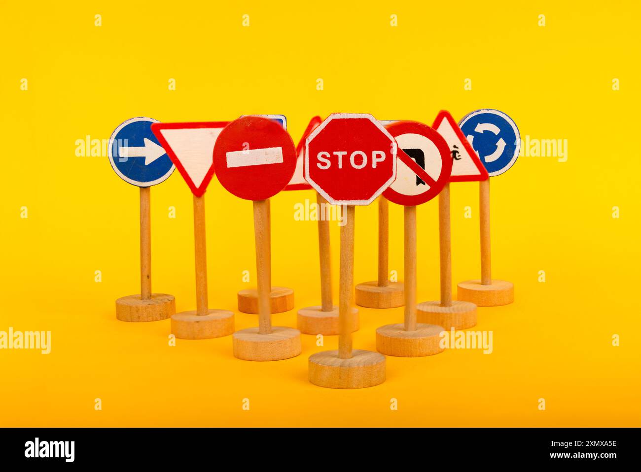 Colorful wooden toy traffic signs are arranged against a bright yellow ...