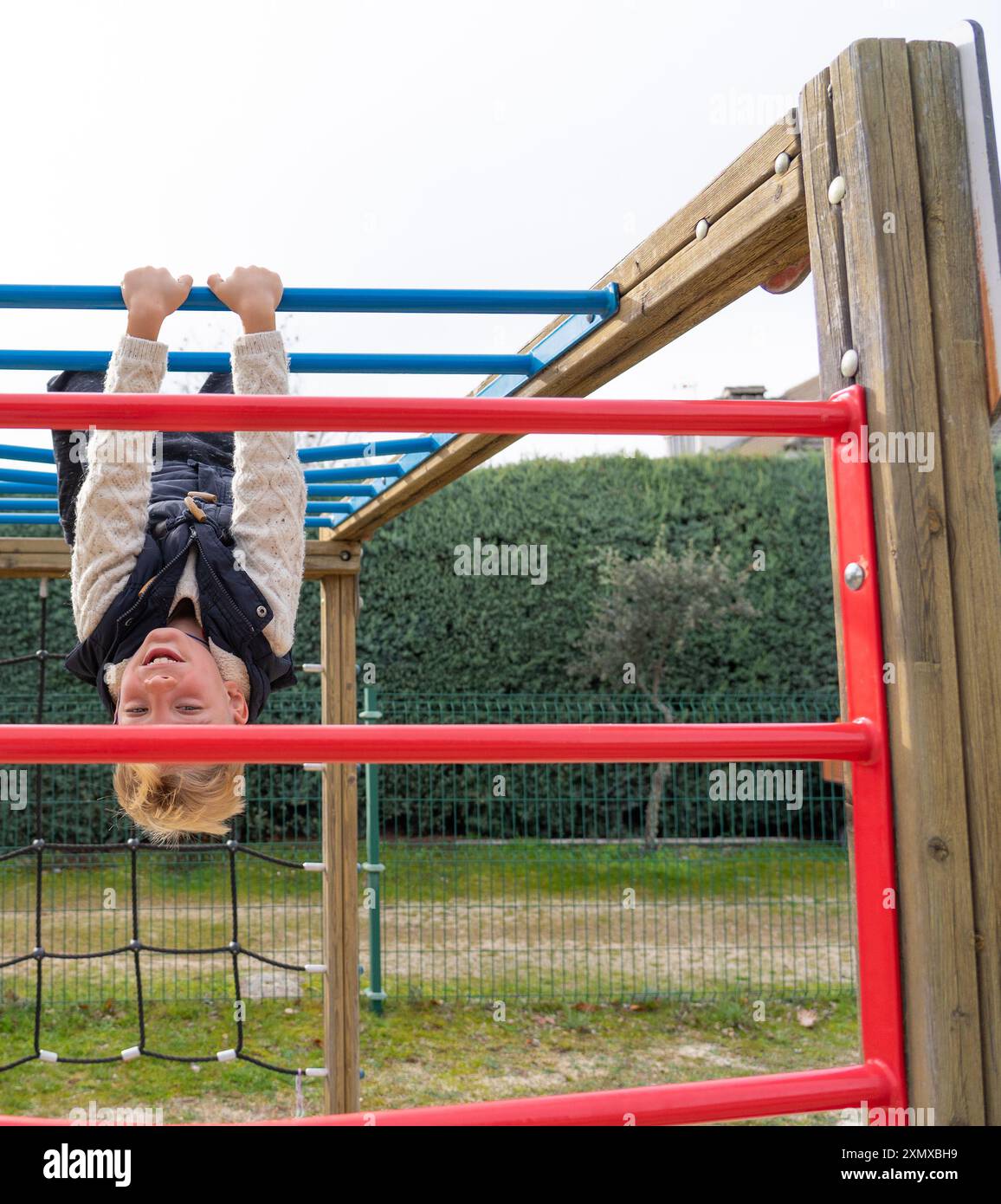 Child hanging upside down on a playground structure Stock Photo - Alamy