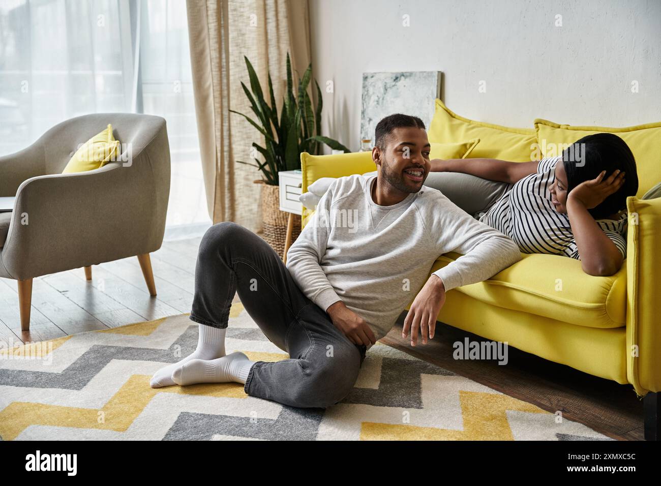 An African American couple relaxes in their living room, enjoying a ...