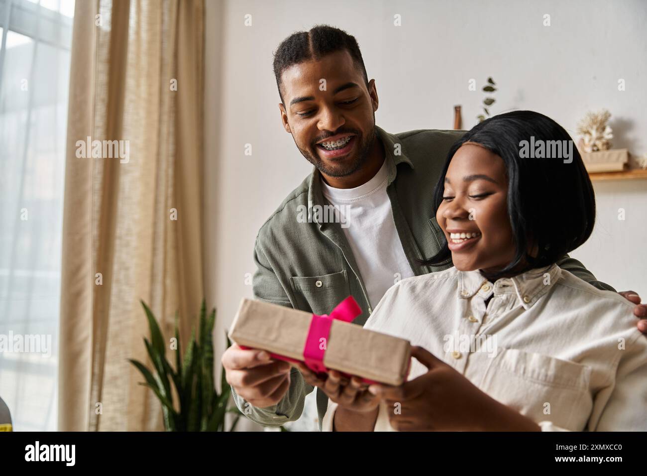 A couple smiles as they exchange a gift at home Stock Photo - Alamy