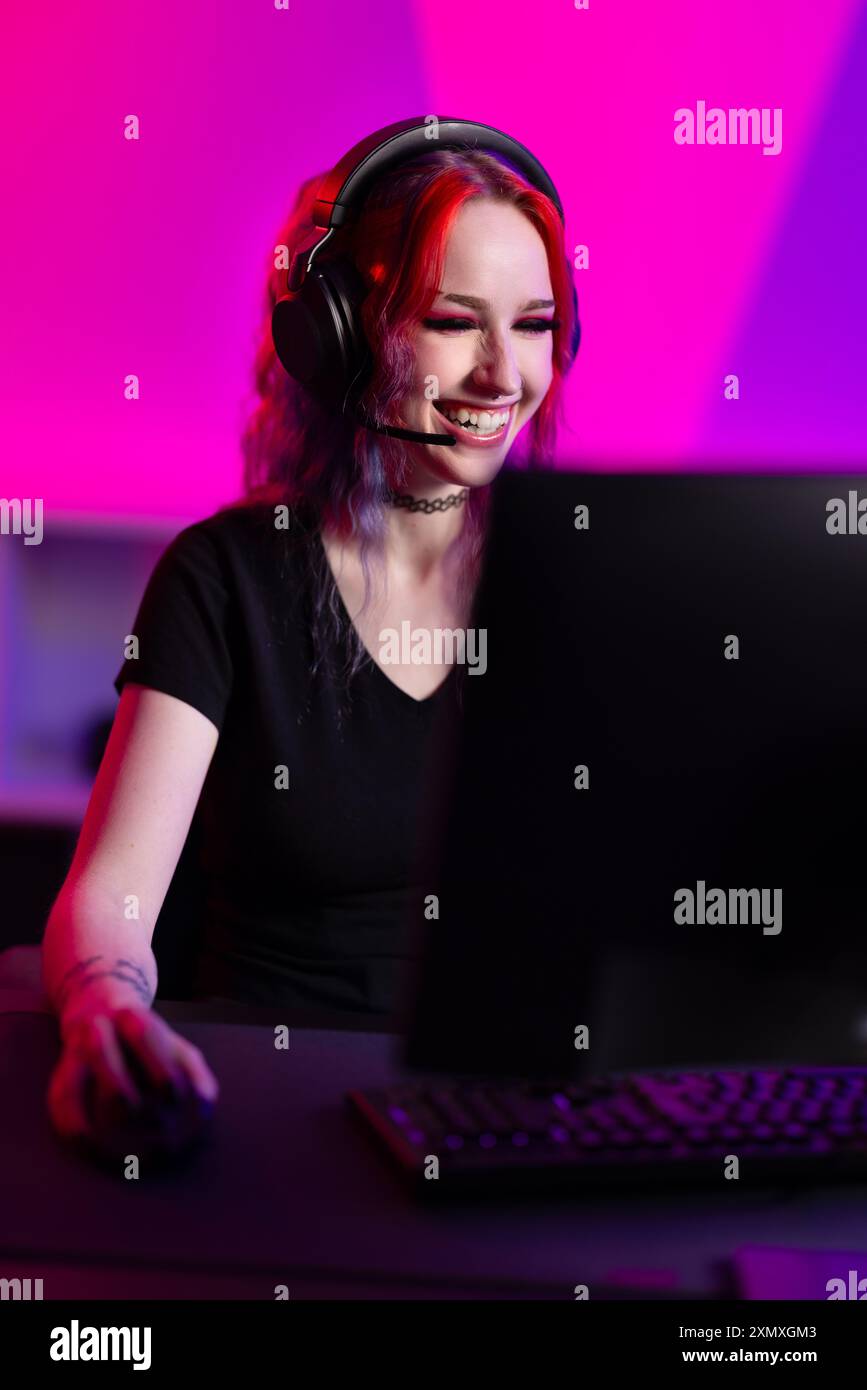 Professional gamer plays enthusiastically in a colorful room with headset and computer setup ...