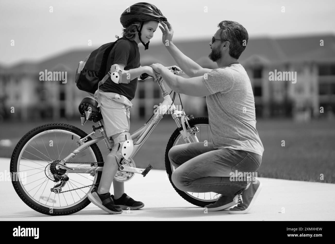 Fathers day and summer family weekend. Father helping his son to wear a ...