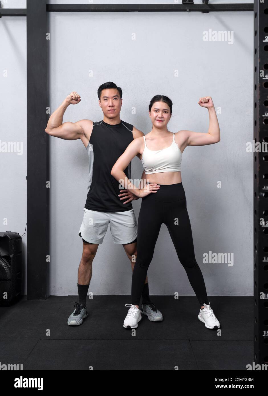 Empowered and strong, a fitness enthusiast couple flexes their biceps under the stark, vibrant ...