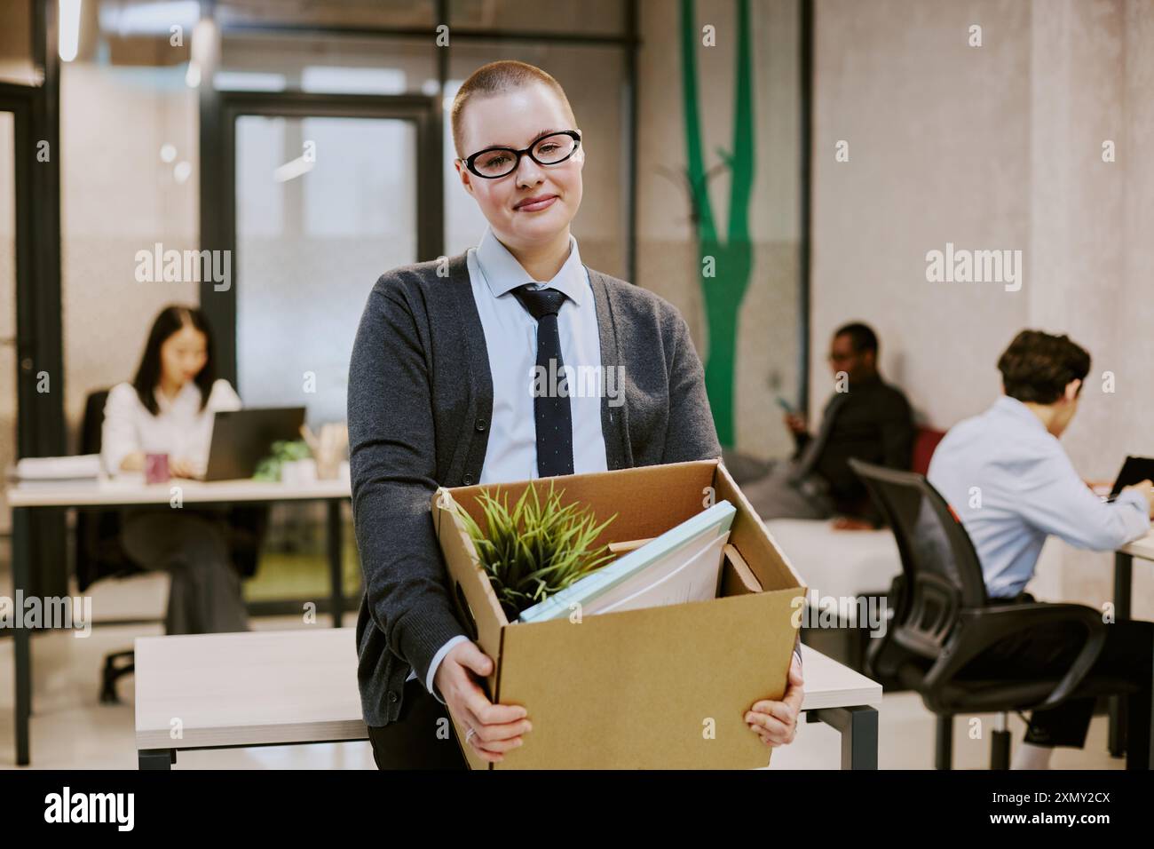 Portrait of young female new employee with stylish buzz cut holding box ...