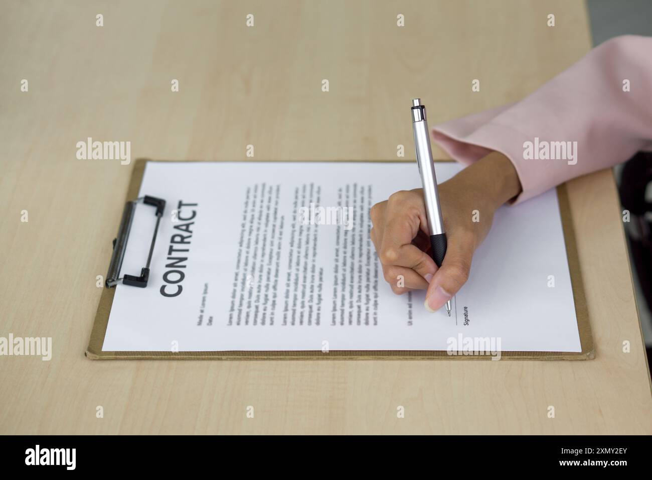 Closeup woman hand signing her name on a contract document on a board ...