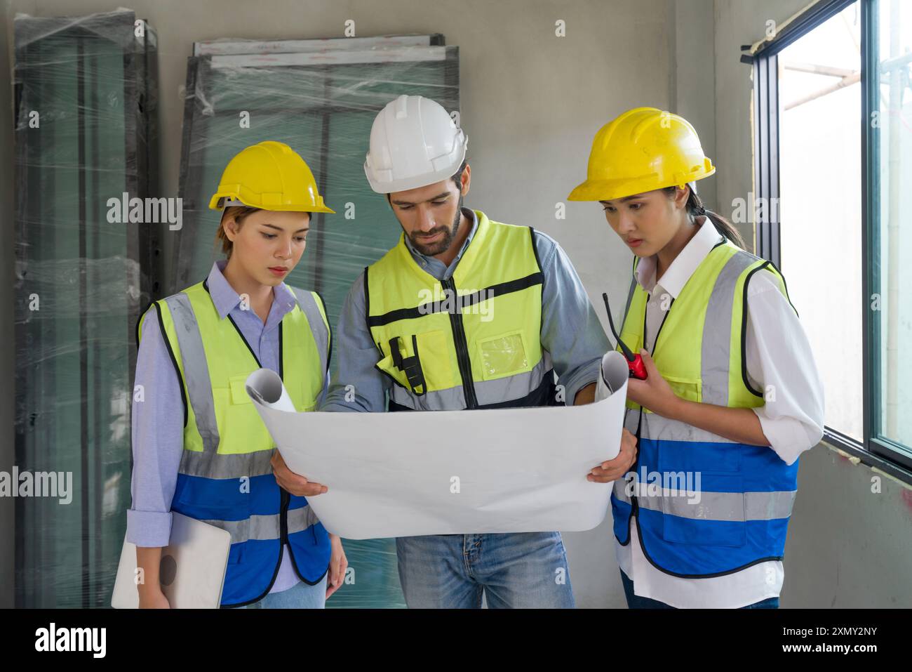 Young caucasian foreman in helmet and safety vest look at the ...
