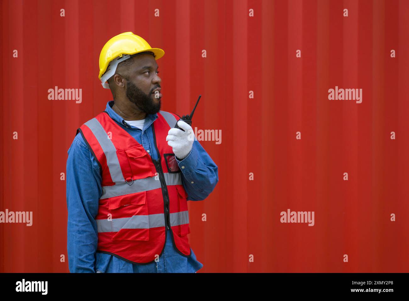 Shipment worker with safety vest and hardhat holding walkie talkie ...