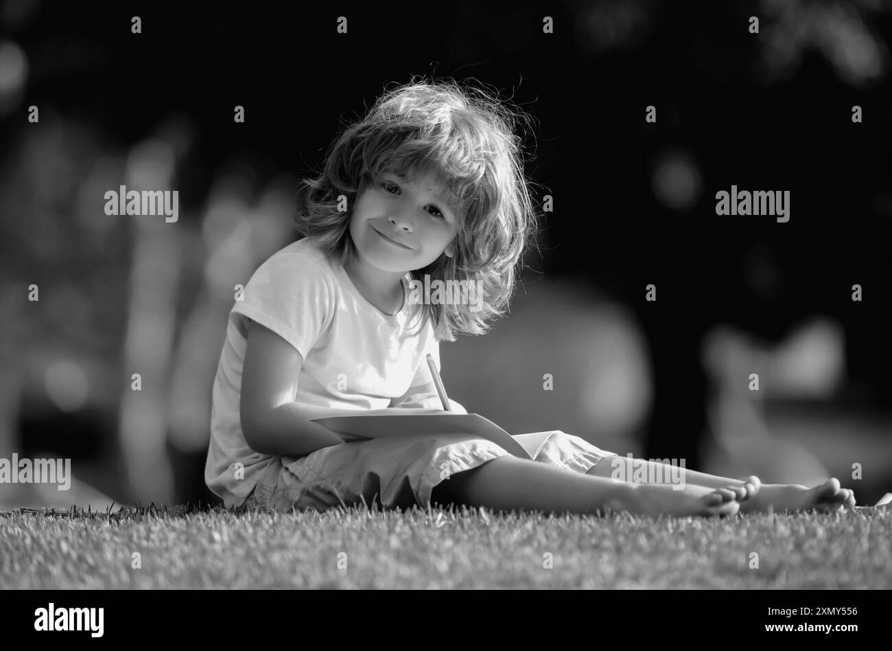 Preschool smiling pupil student boy writing to notebook in park on ...
