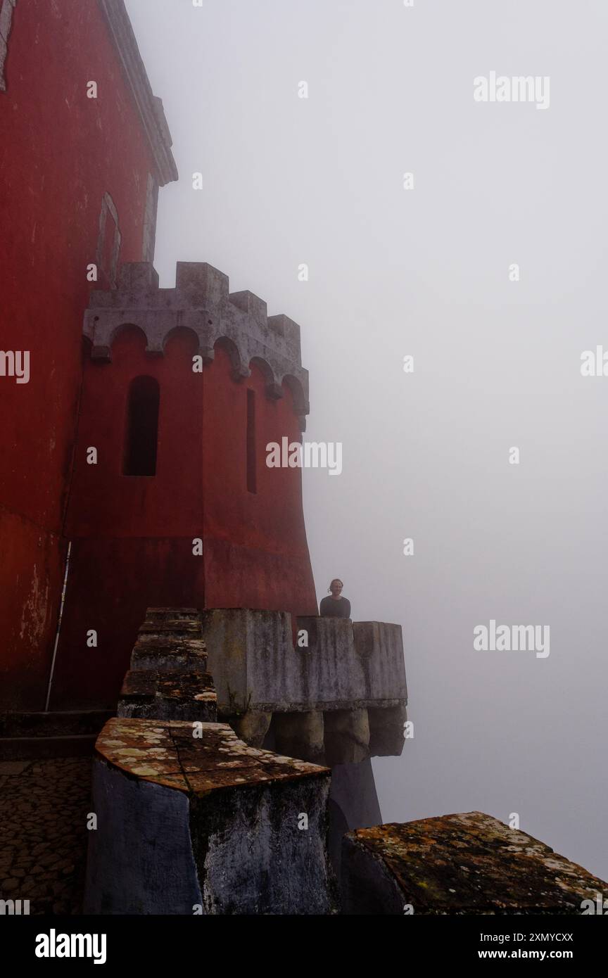 The weathered red walls of a turret with a lone silhouette of a person ...