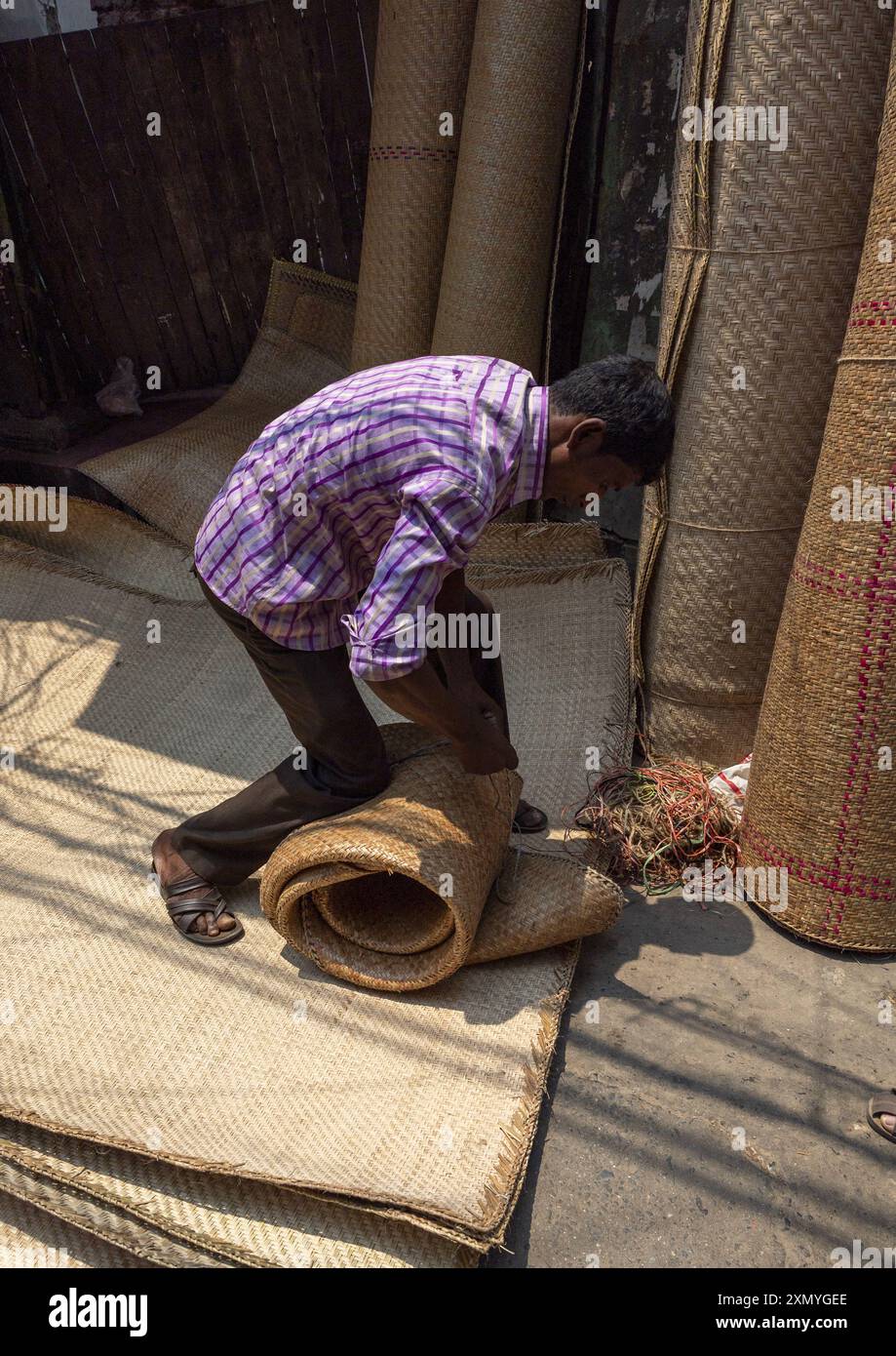 Bangladeshi man packing jute rugs in the street, Dhaka Division, Dhaka ...