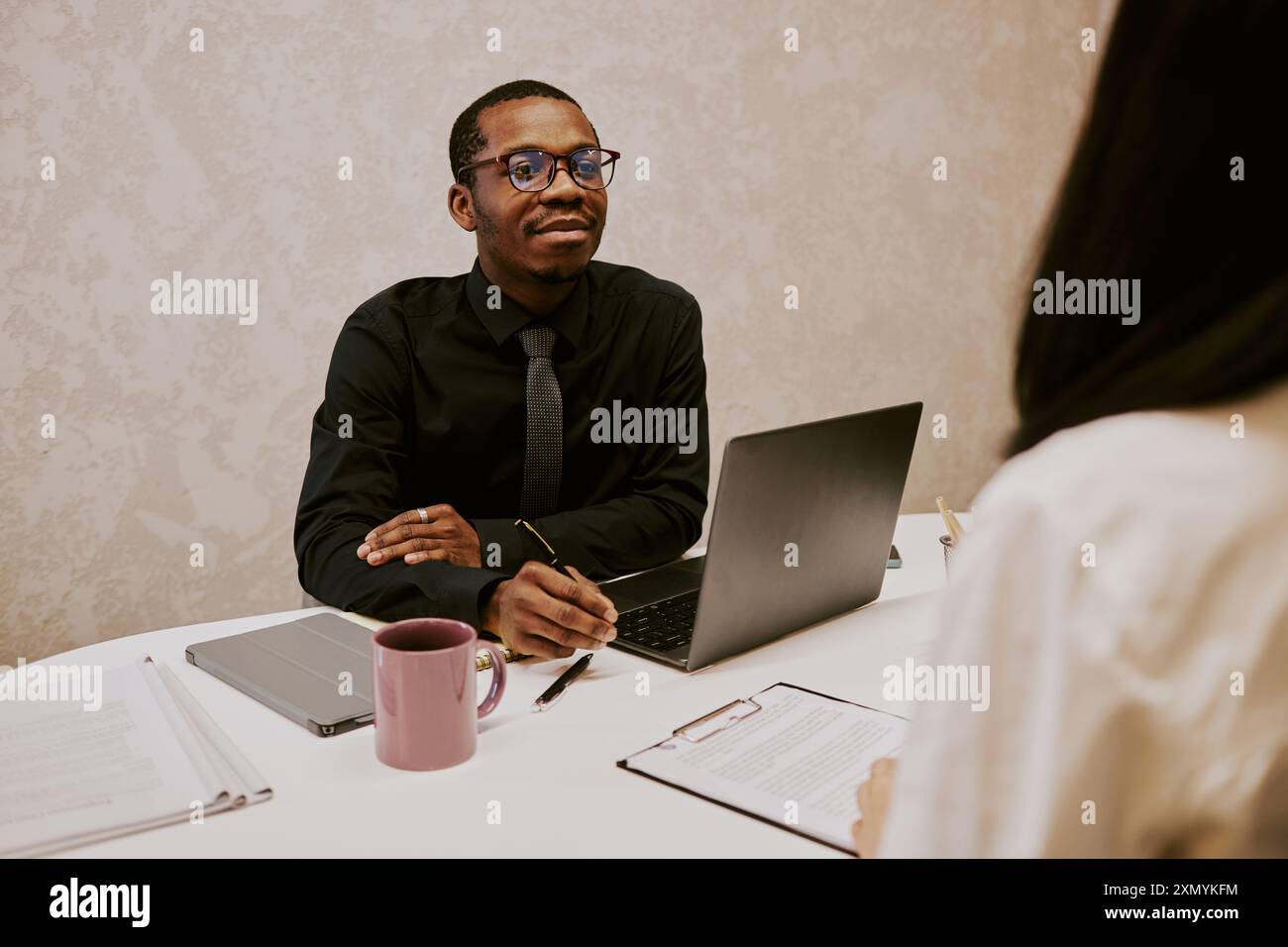Over shoulder shot of young African American HR manager sitting at desk ...
