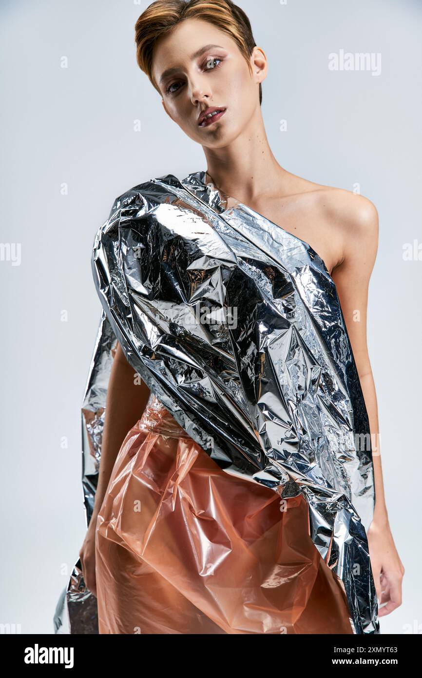 A woman poses in a studio, wearing a shimmering silver fabric and a ...