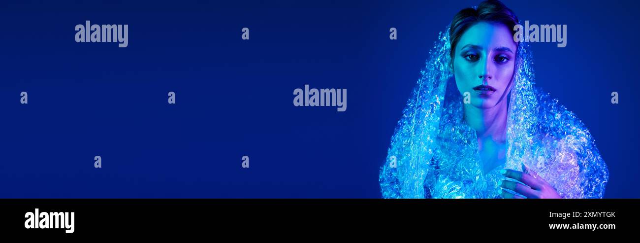 A woman, bathed in blue light, stands enveloped in a shimmering ...