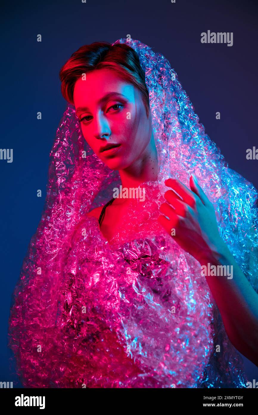 A woman poses in a studio with colorful lights, wrapped in bubble wrap ...