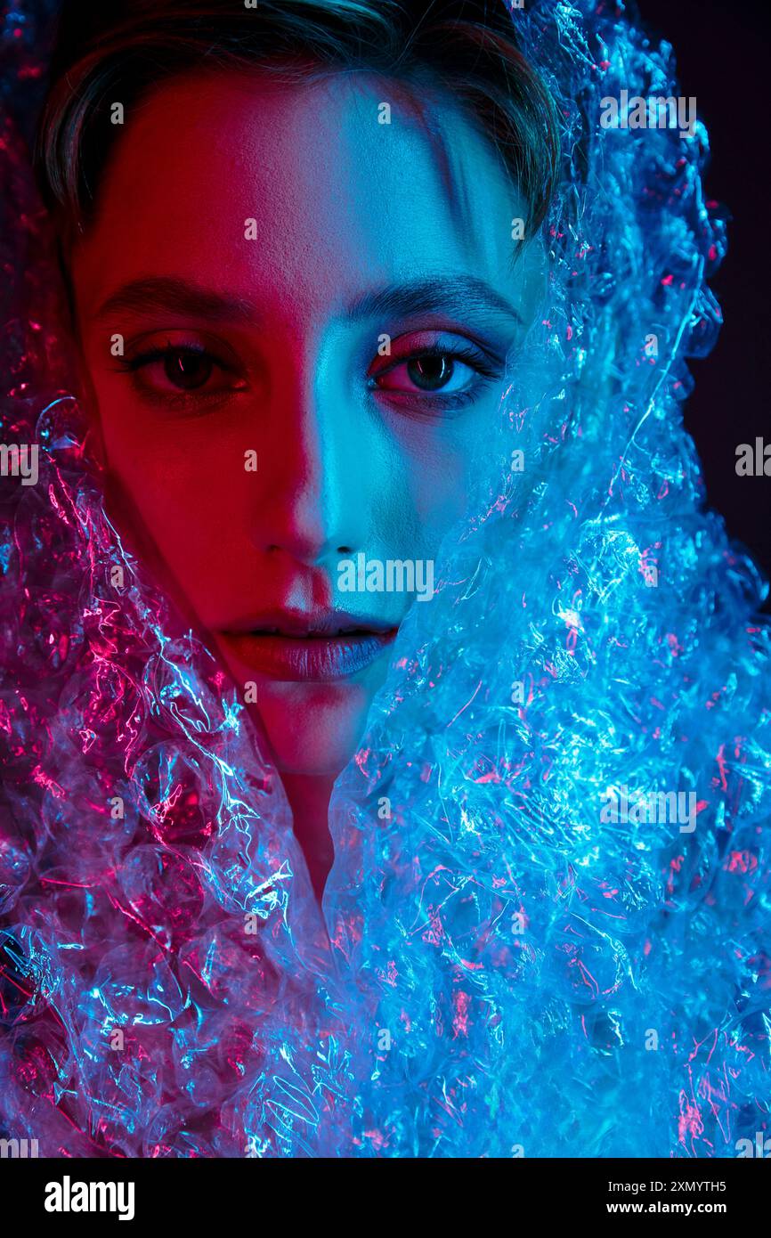 A woman's face is illuminated by pink and blue light, obscured by a ...