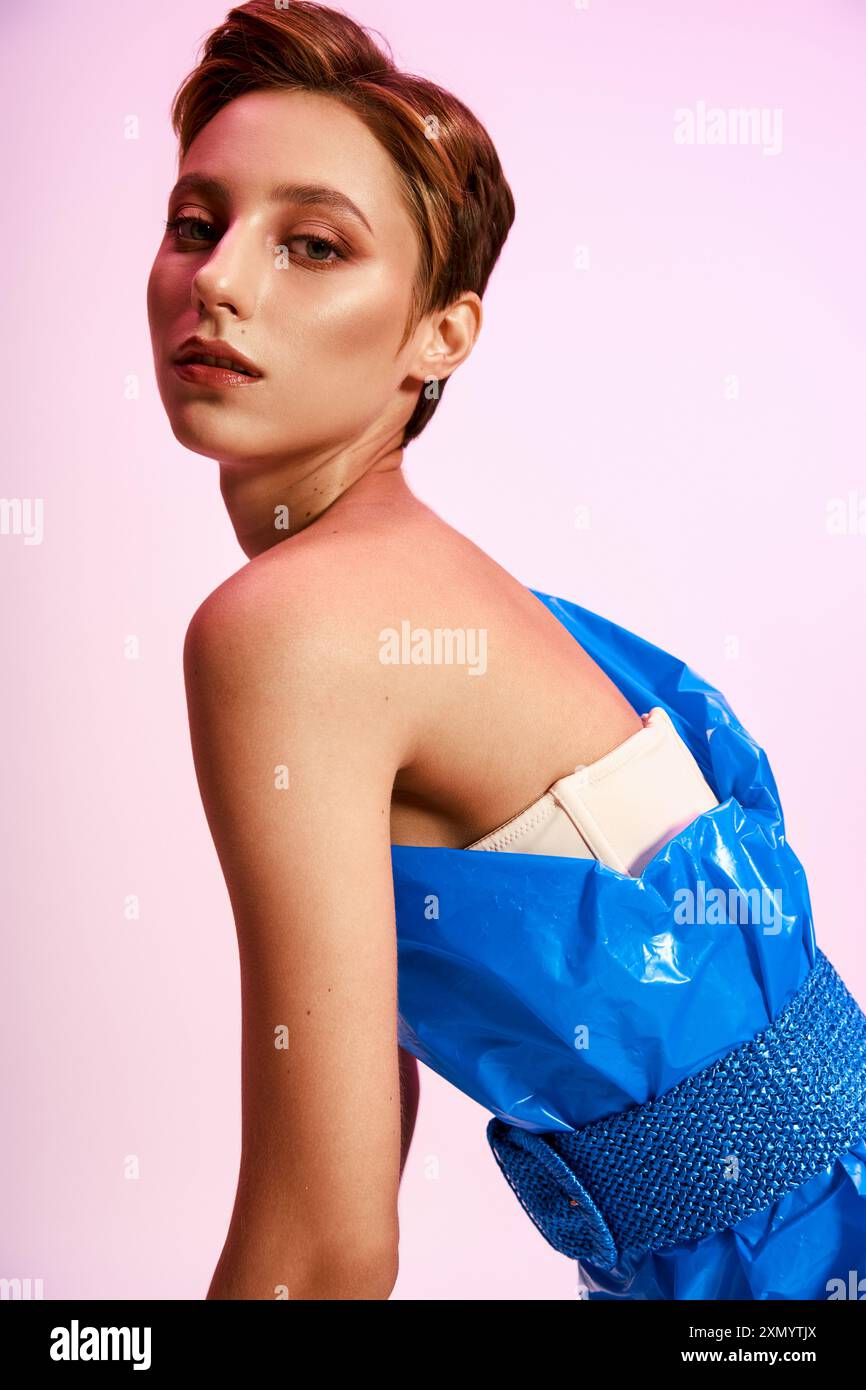 A young woman poses in a blue plastic dress, showcasing the beauty of ...