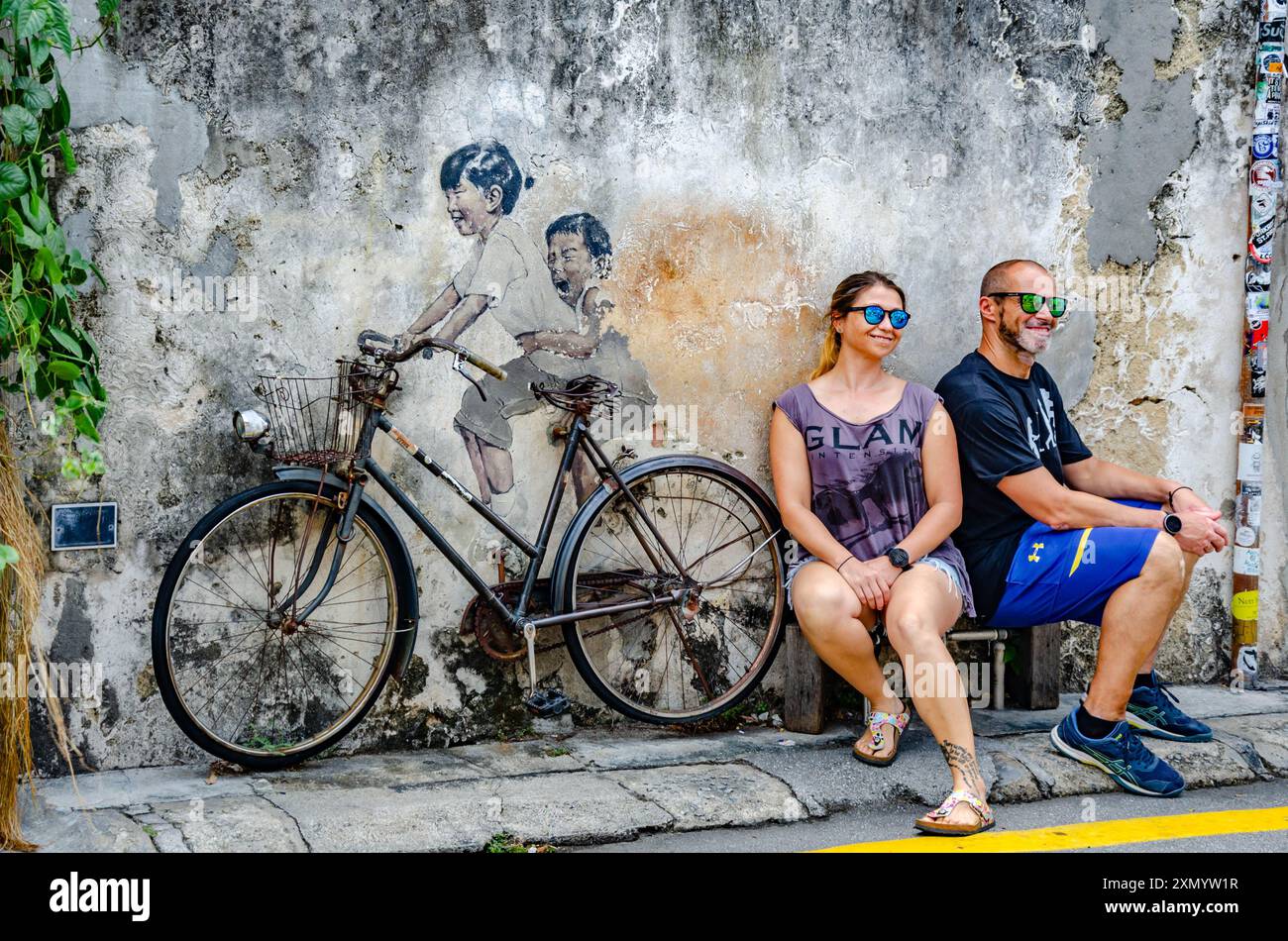 Tourists pose for a photograph next a street art installation featuring children on a bicycle on ...