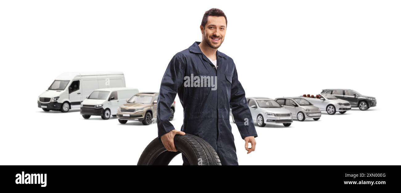 Auto mechanic smiling and holding a tire at a car park isolated on ...