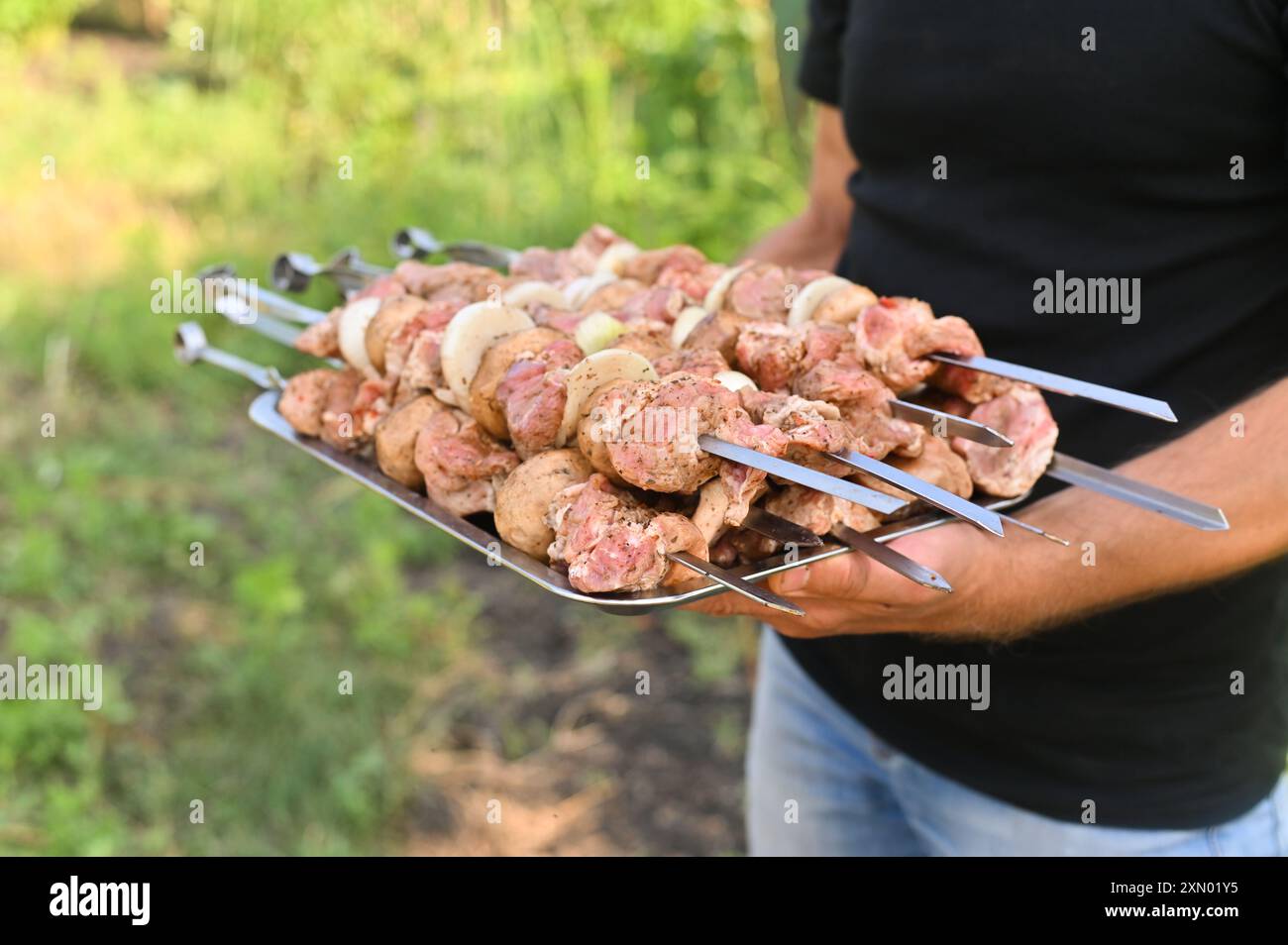 a man puts a skewer with meat on the grill Stock Photo - Alamy