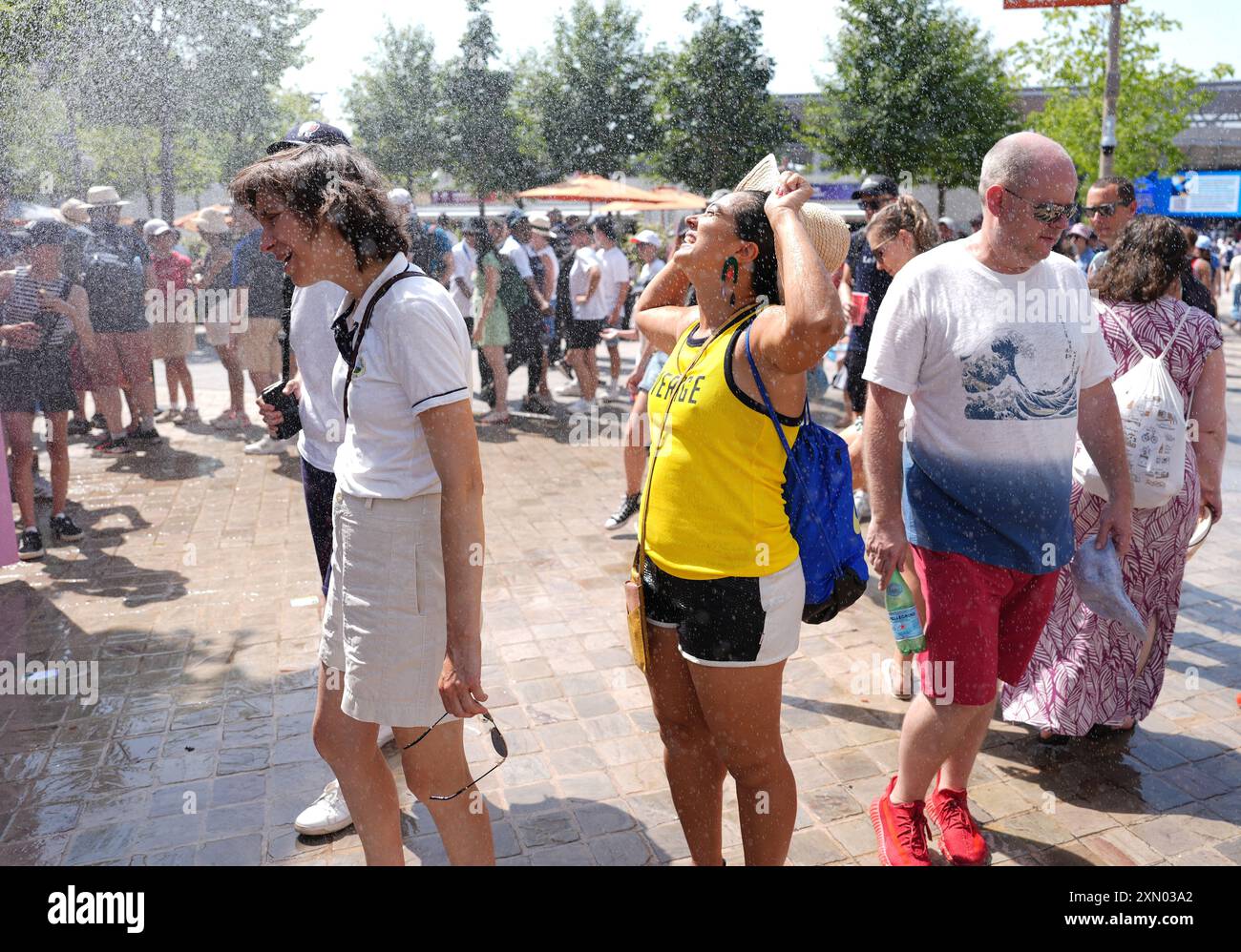Spectators cool off in a mist of water at Roland-Garros on the fourth ...