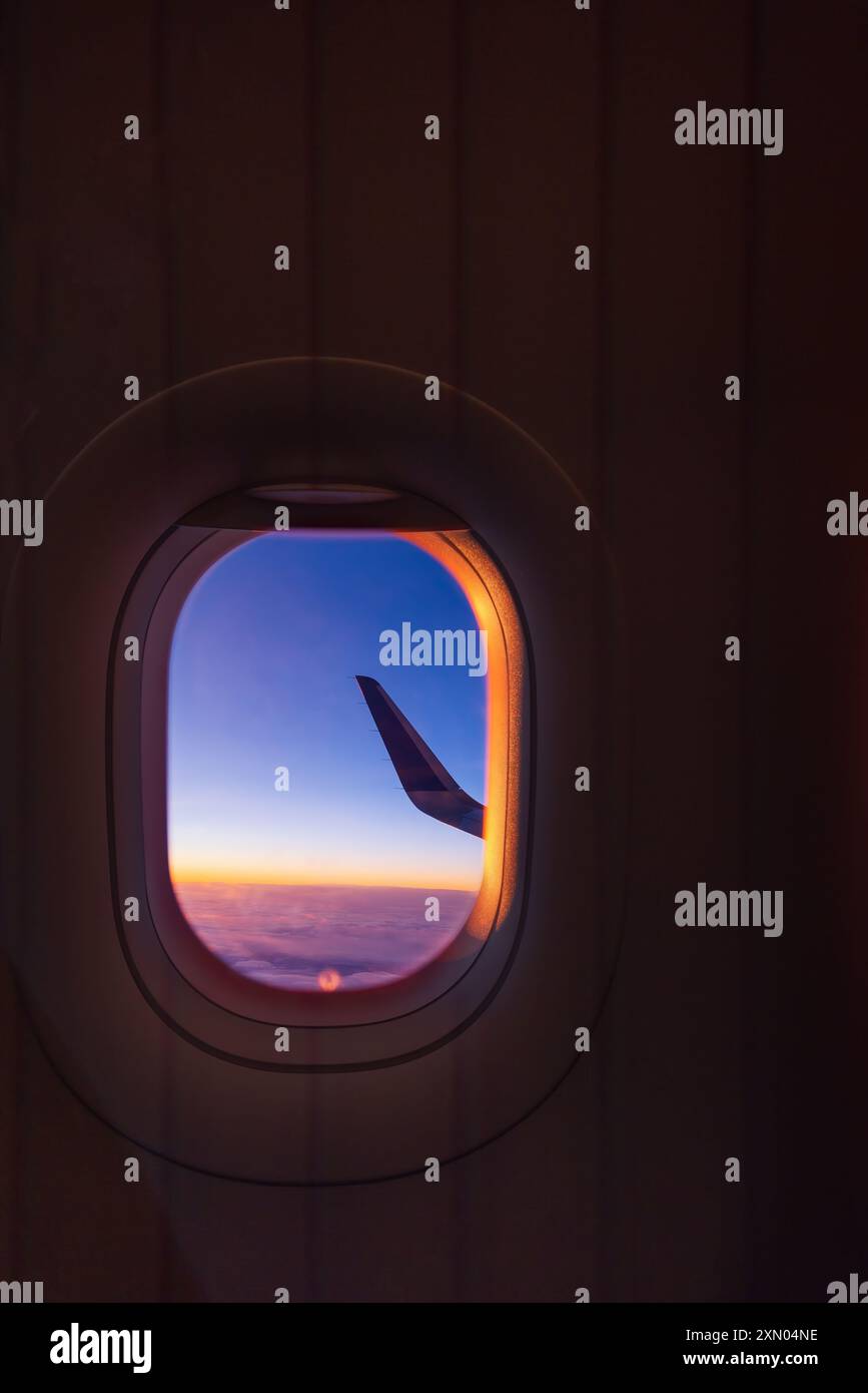 Airplane flying over color sky clouds during scenic sunset or sunrise ...