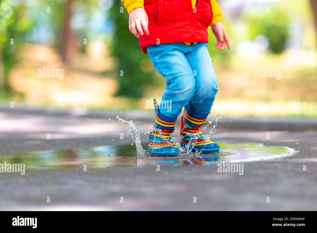 Kid child jumping puddle water splash hi-res stock photography and ...