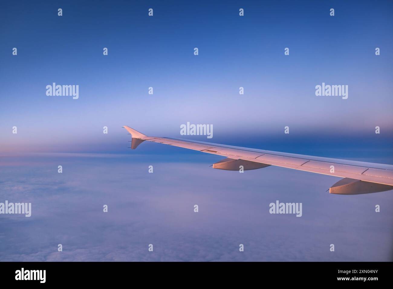 Airplane flying over color sky clouds during scenic sunset or sunrise ...