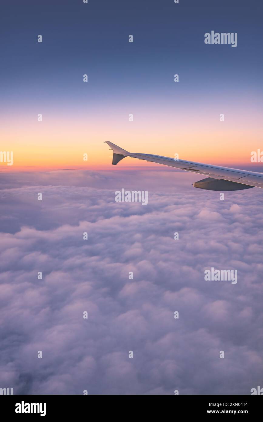 Airplane flying over color sky clouds during scenic sunset or sunrise ...