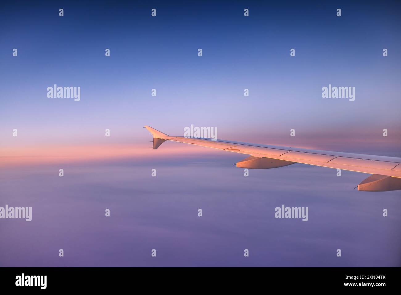 Airplane flying over color sky clouds during scenic sunset or sunrise ...