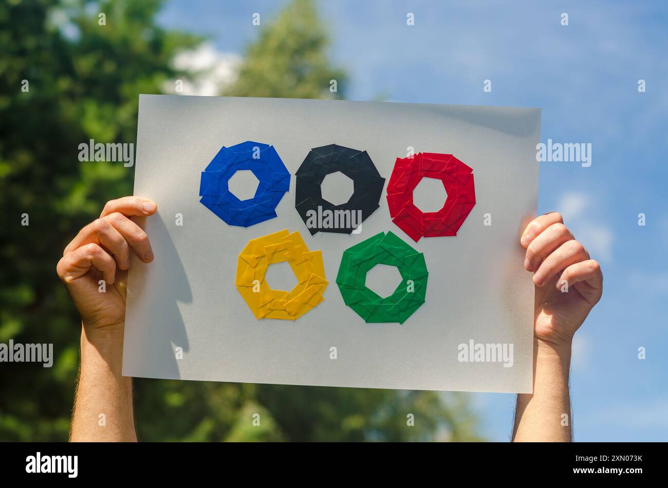 hands hold the banner with olympic rings on sky background . High ...