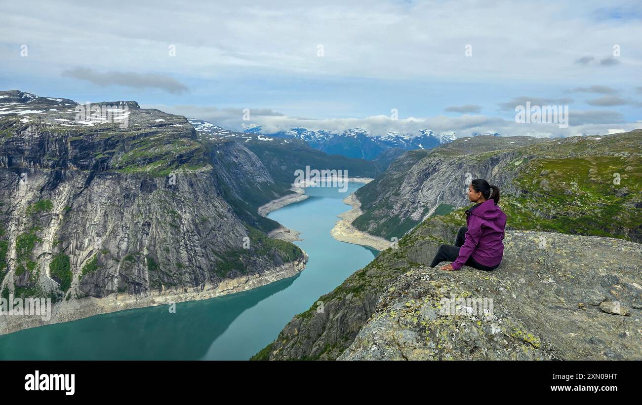 A traveler sits peacefully on a rocky ledge, gazing at the stunning ...