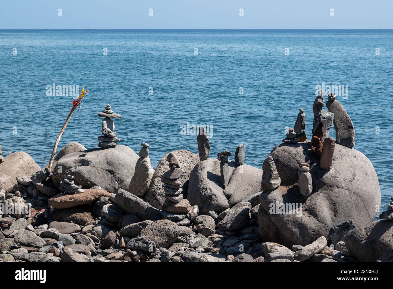 Stone towers made of beach pebbles. Coast of the Atlantic ocen. Blue ...