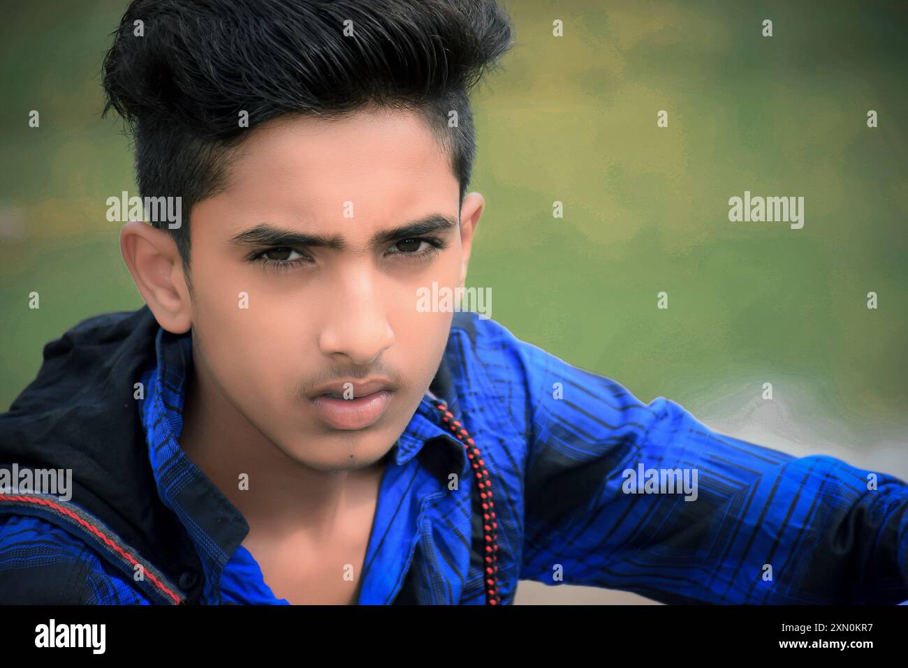 Indian model boy in blue dress posing, outdoor greenery background ...
