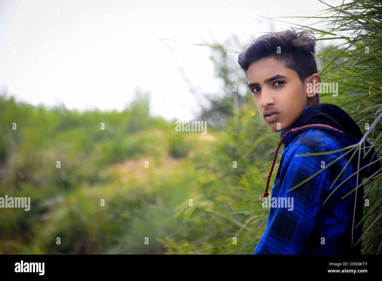 Indian model boy in blue dress posing, outdoor greenery background ...