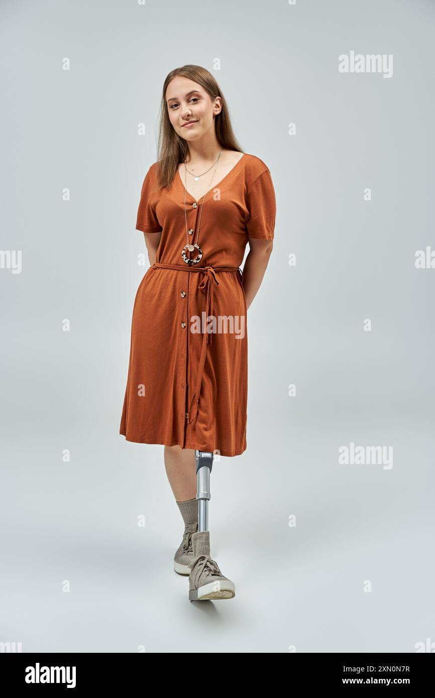 A woman in an orange dress walks forward with her prosthetic leg Stock ...