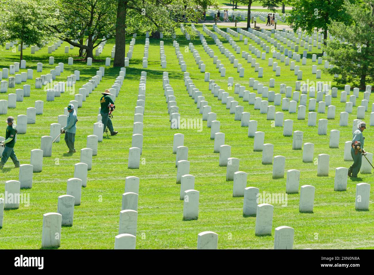 Arlington National Cemetery, Virginia, USA. Garden workers on strimming ...