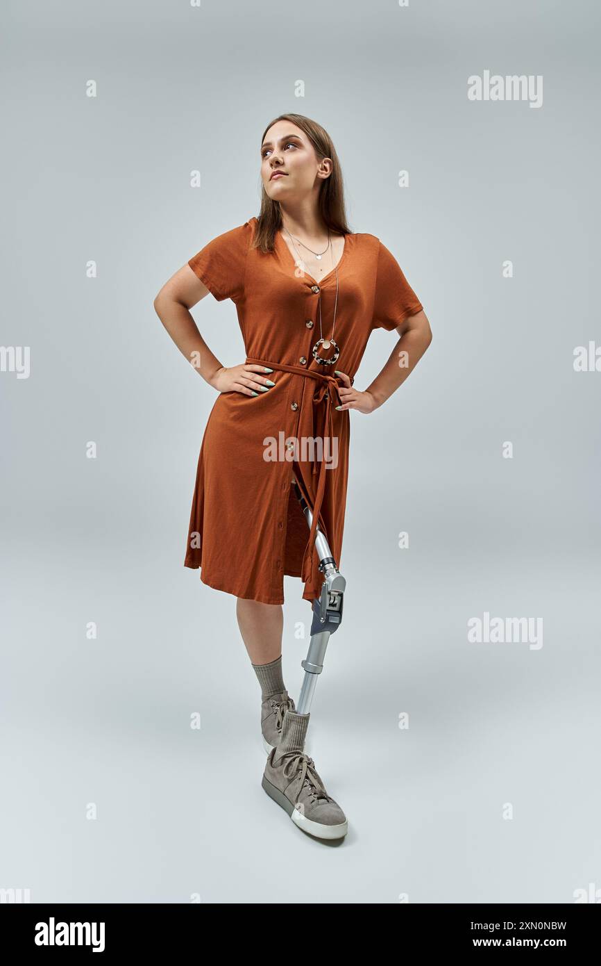 A woman in a rust-colored dress stands confidently, her prosthetic leg ...