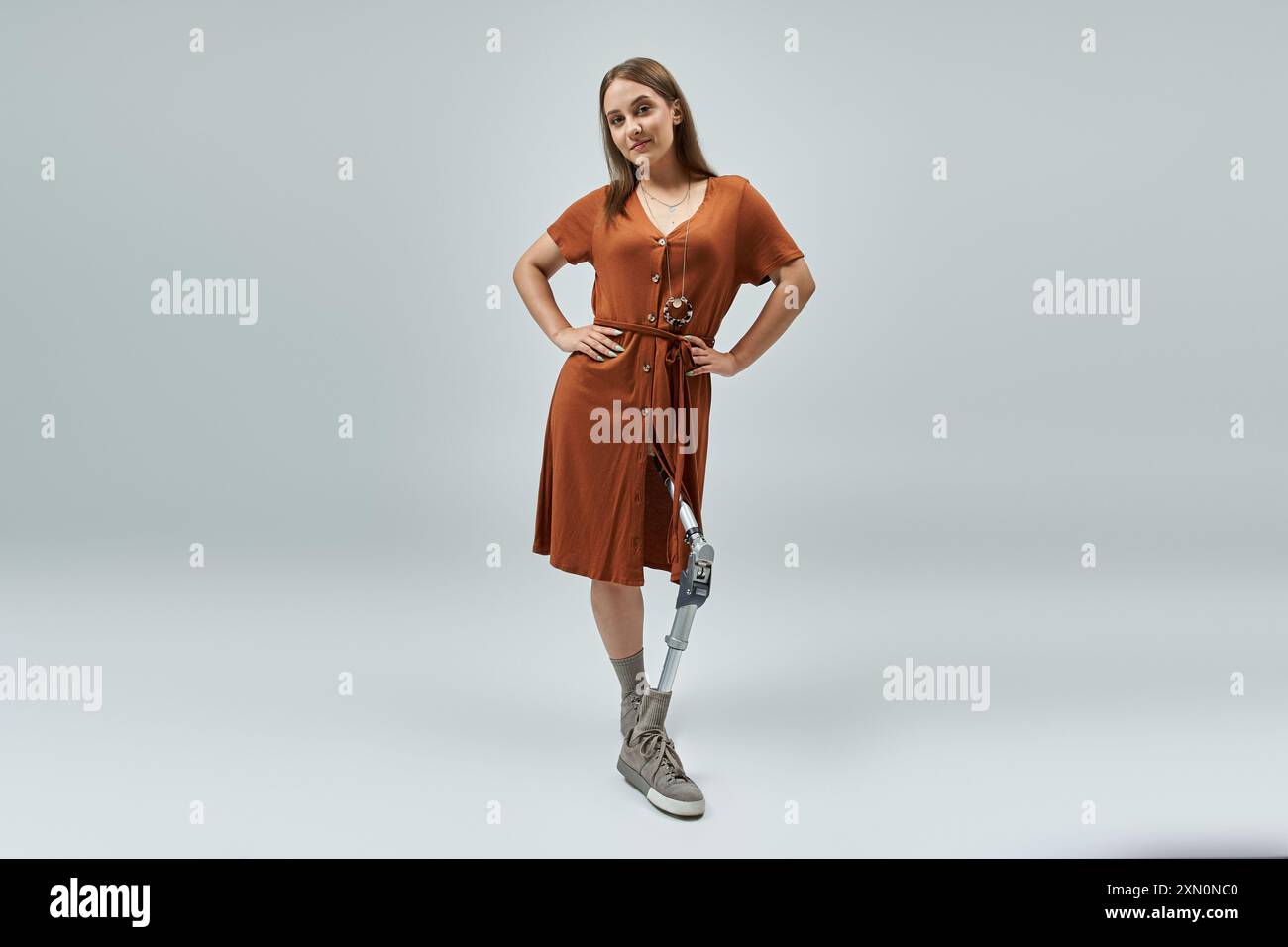 Woman in rust dress poses coolly, hand on hips, flaunting prosthetic ...