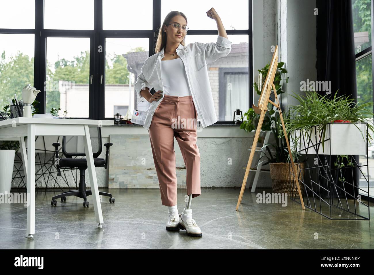 Woman with prosthetic leg stands confidently in office, arm raised in ...