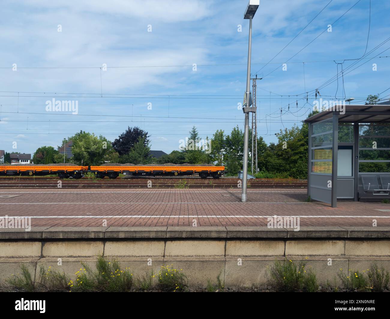 A freight train transports cargo past a nearly empty train station ...