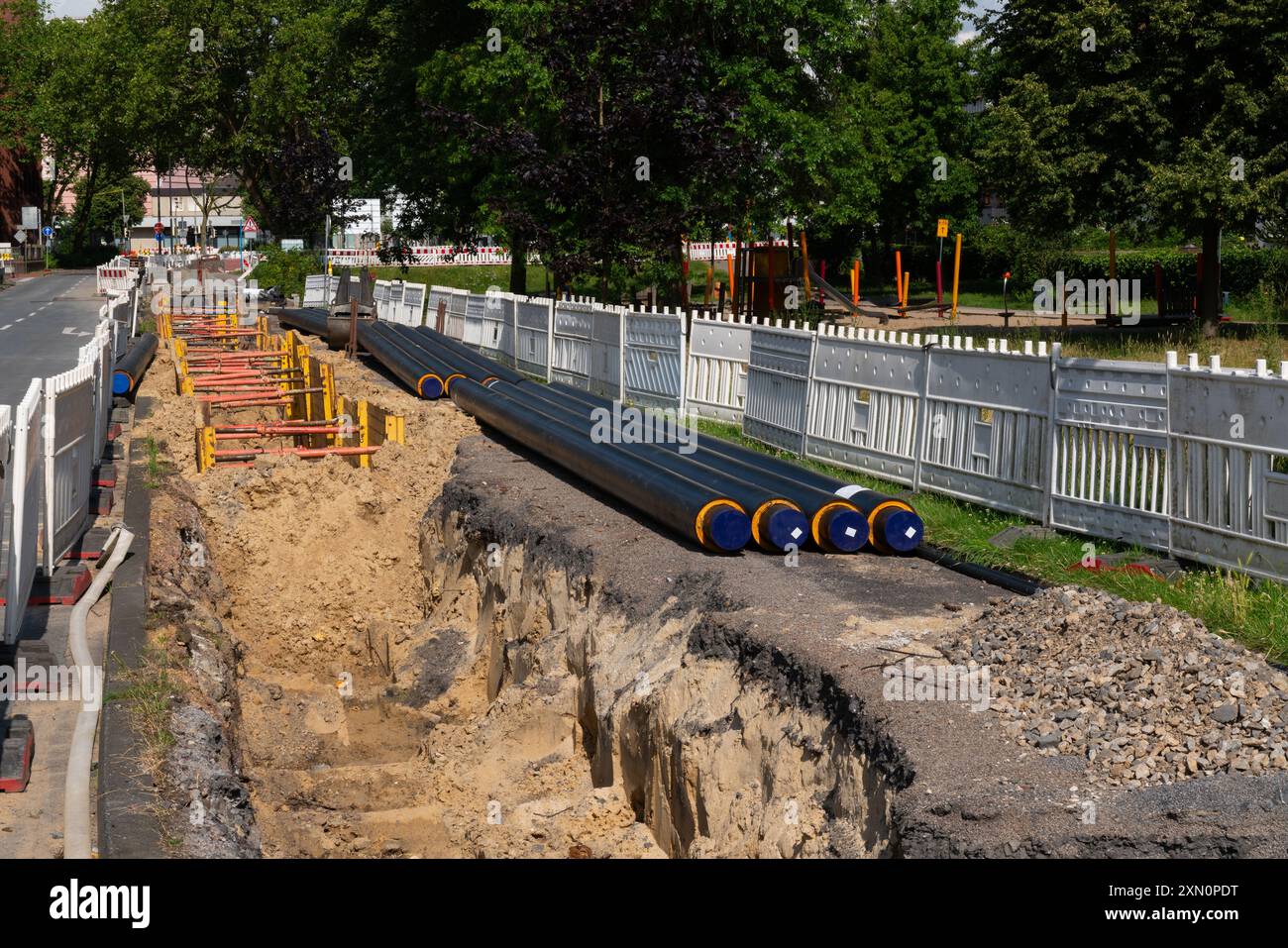 An urban street undergoing construction features an excavated trench ...