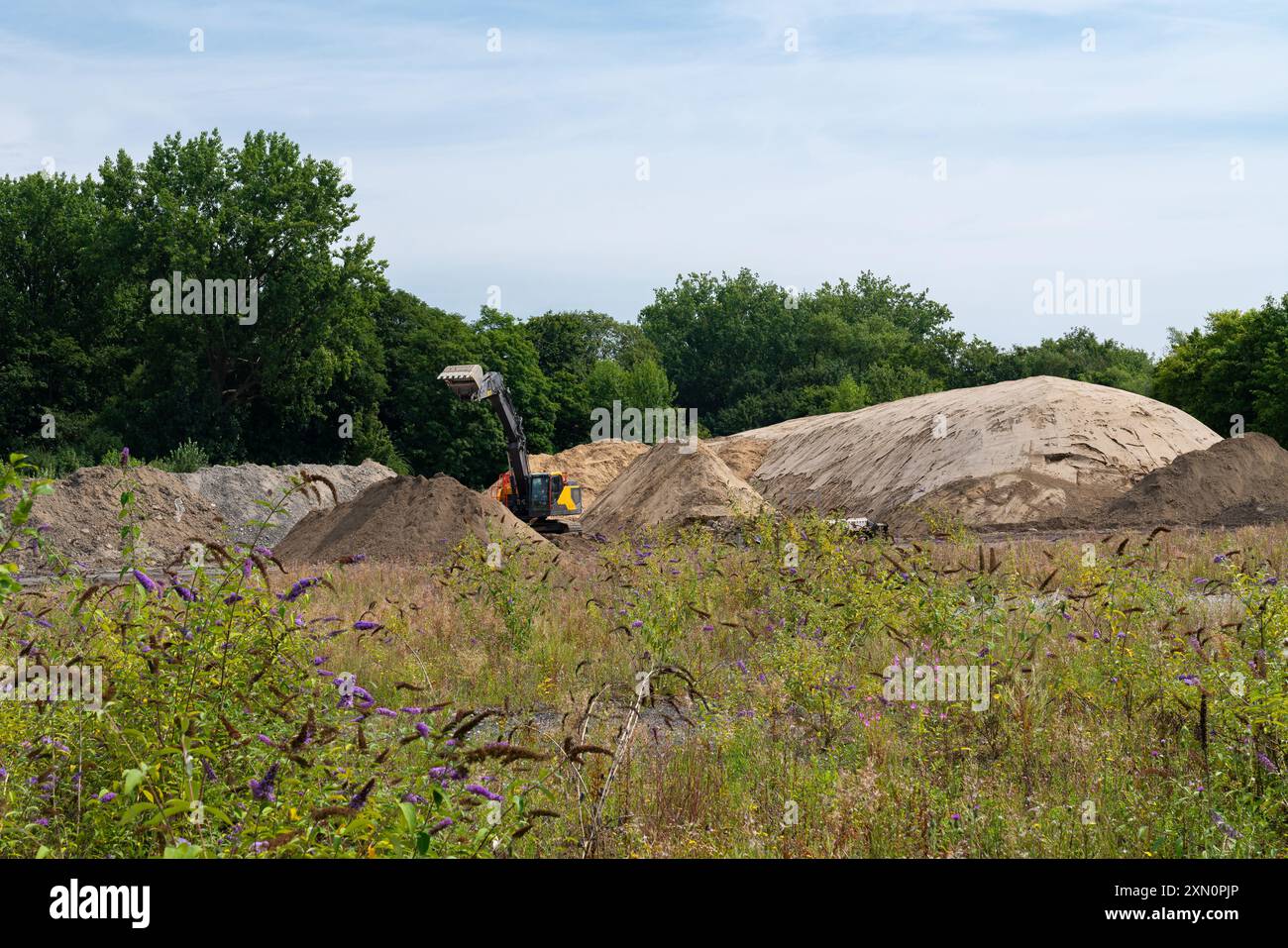 An excavator operates on a construction site, moving dirt and sand ...
