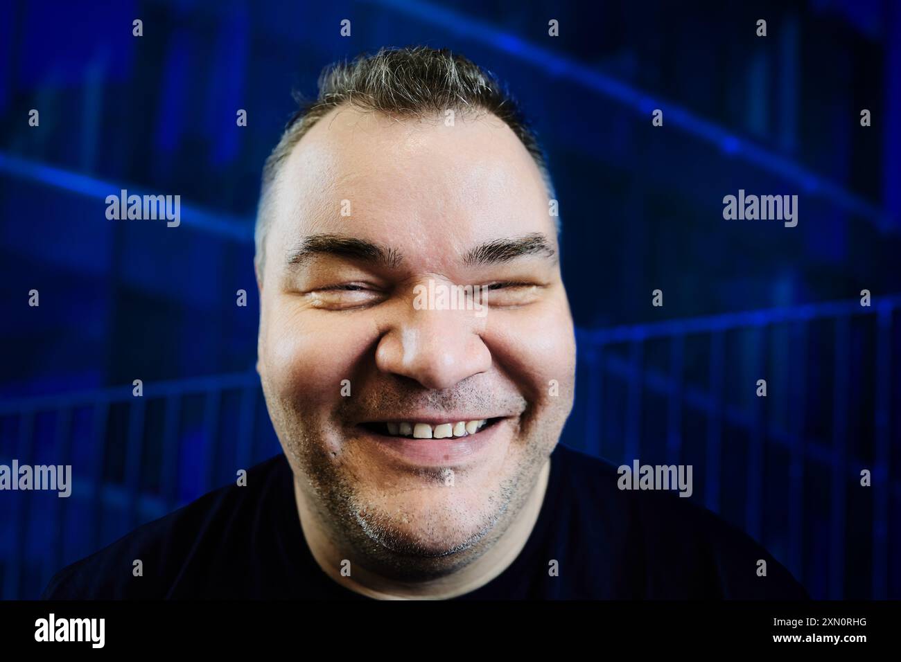 Toothy smile of large white man in his 40s, close-up portrait on blue ...